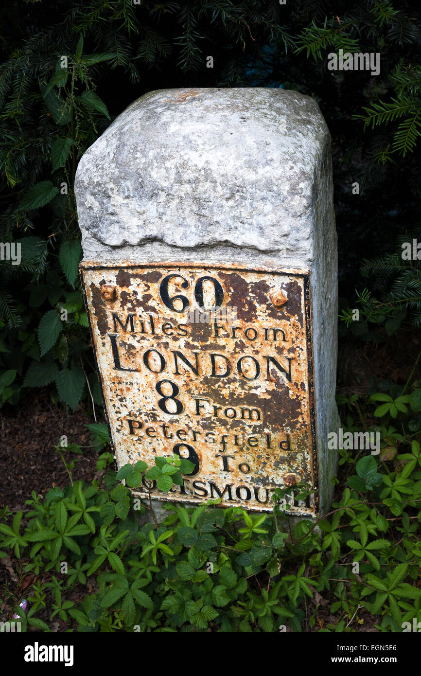 Old worn traditional milestone marker with metal plate stating 60 miles ...