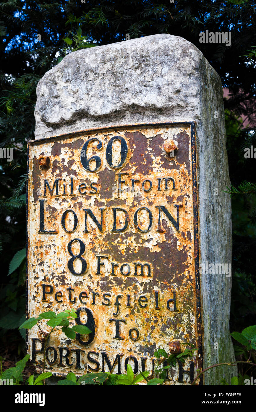 Old worn traditional milestone marker with metal plate stating 60 miles ...