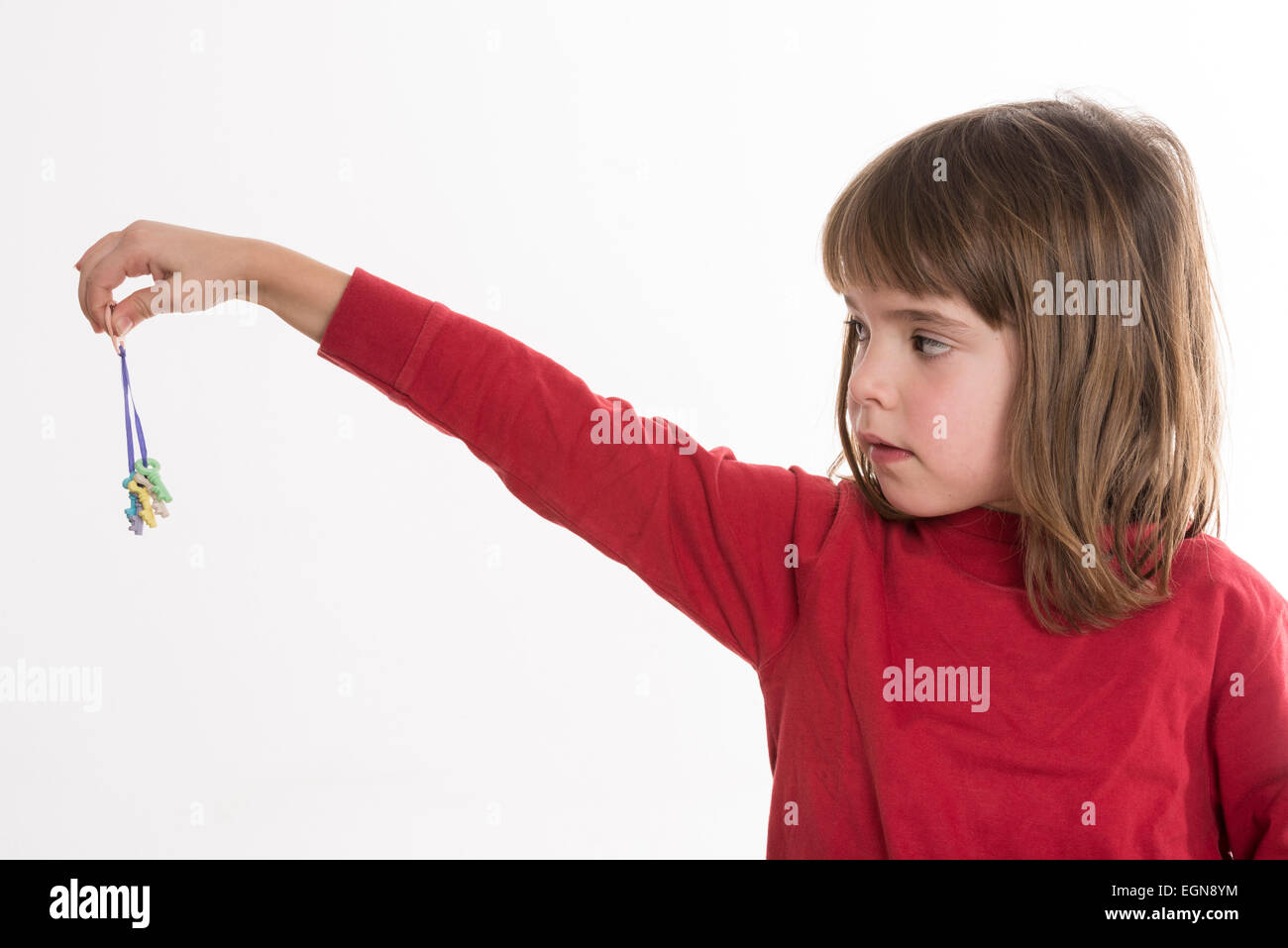 Little girl looking at a small colored keys isolated on white ...