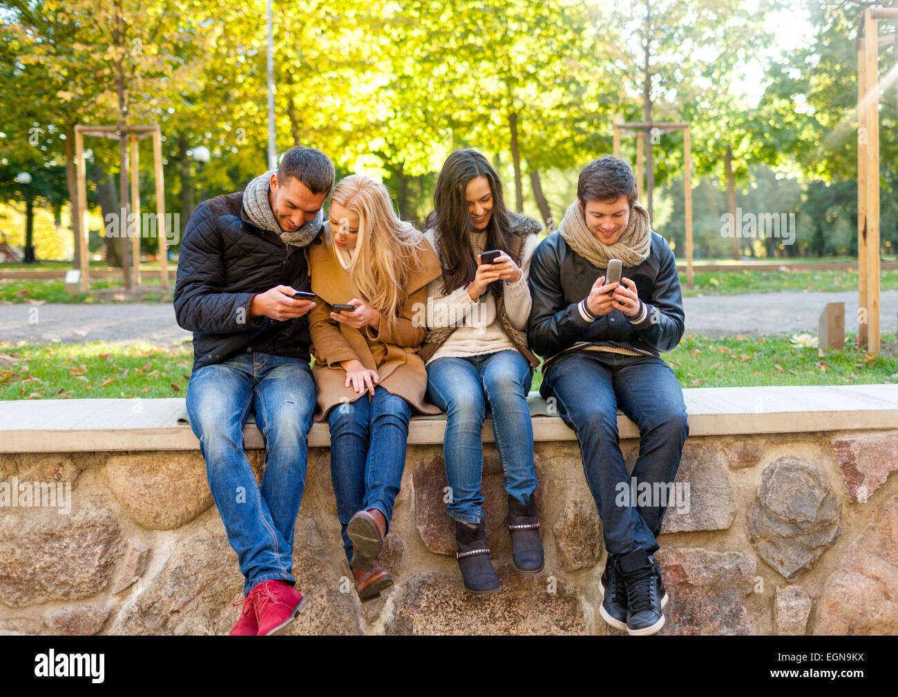 smiling friends with smartphones in city park Stock Photo - Alamy
