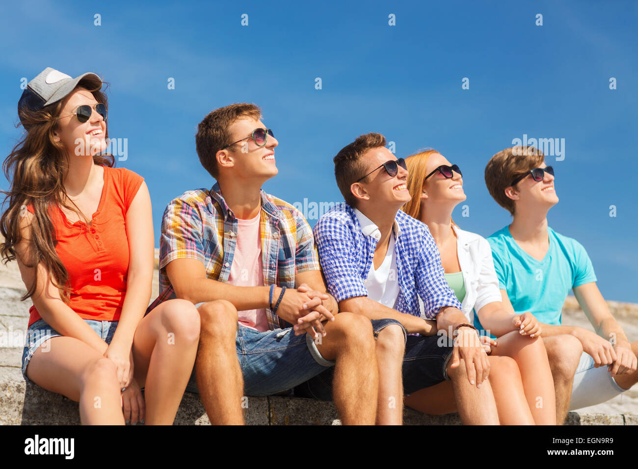 group of smiling friends sitting on city street Stock Photo - Alamy