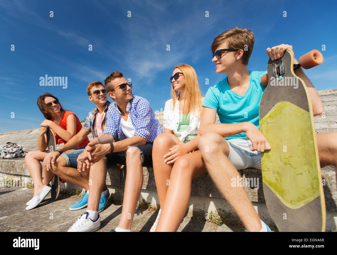 group of smiling friends sitting on city street Stock Photo - Alamy