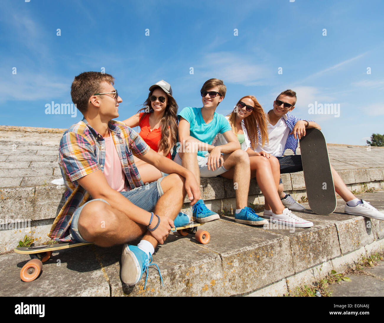 group of smiling friends sitting on city street Stock Photo - Alamy
