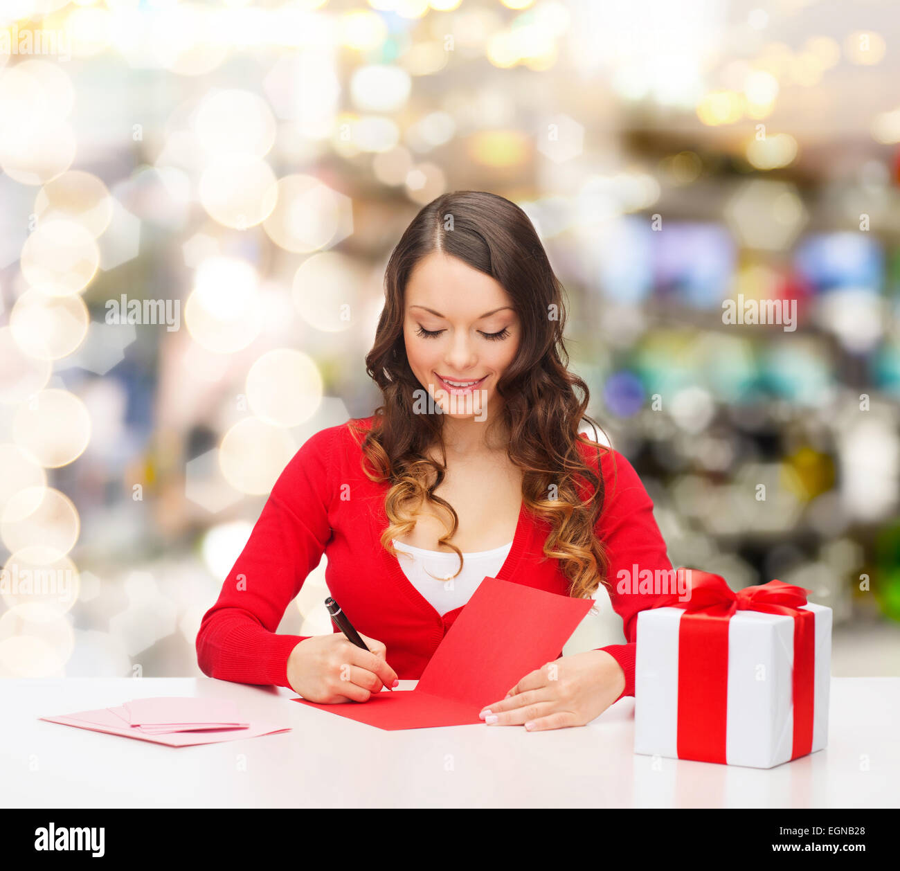 smiling woman with gift box writing letter Stock Photo - Alamy