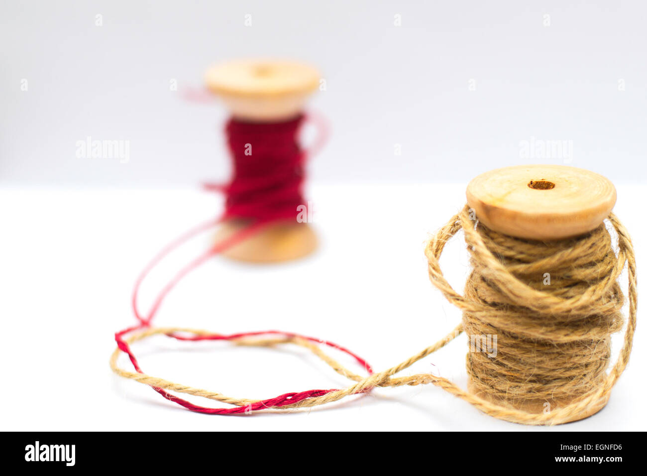Red wool and beige wool thread linked by two cotton reels Stock Photo ...