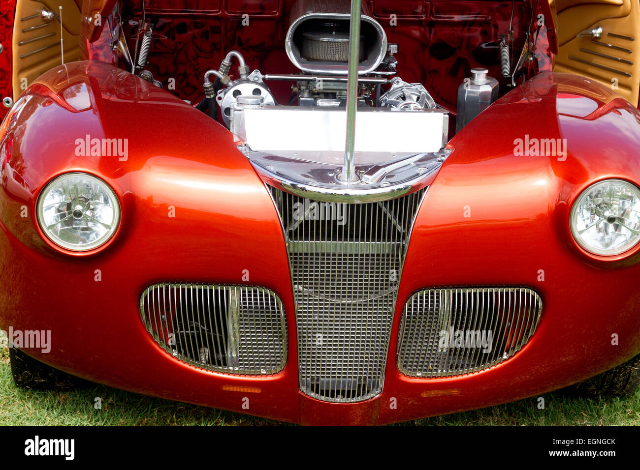 A closeup front view of a customized 1940 Ford hotrod with hood up ...
