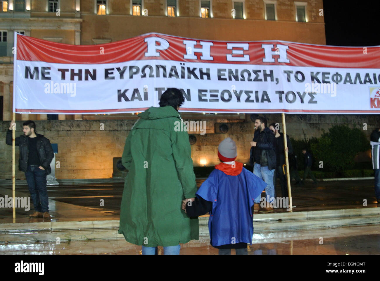 Athens, Greece. 27th February, 2015. A woman and her son watch a banner ...
