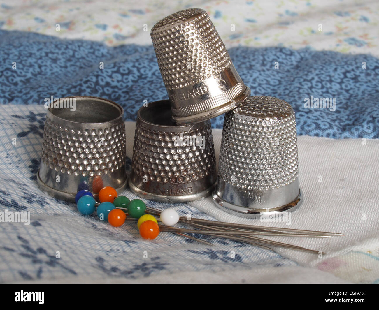 Four different thimbles and a group of coloured pins on some patchwork ...
