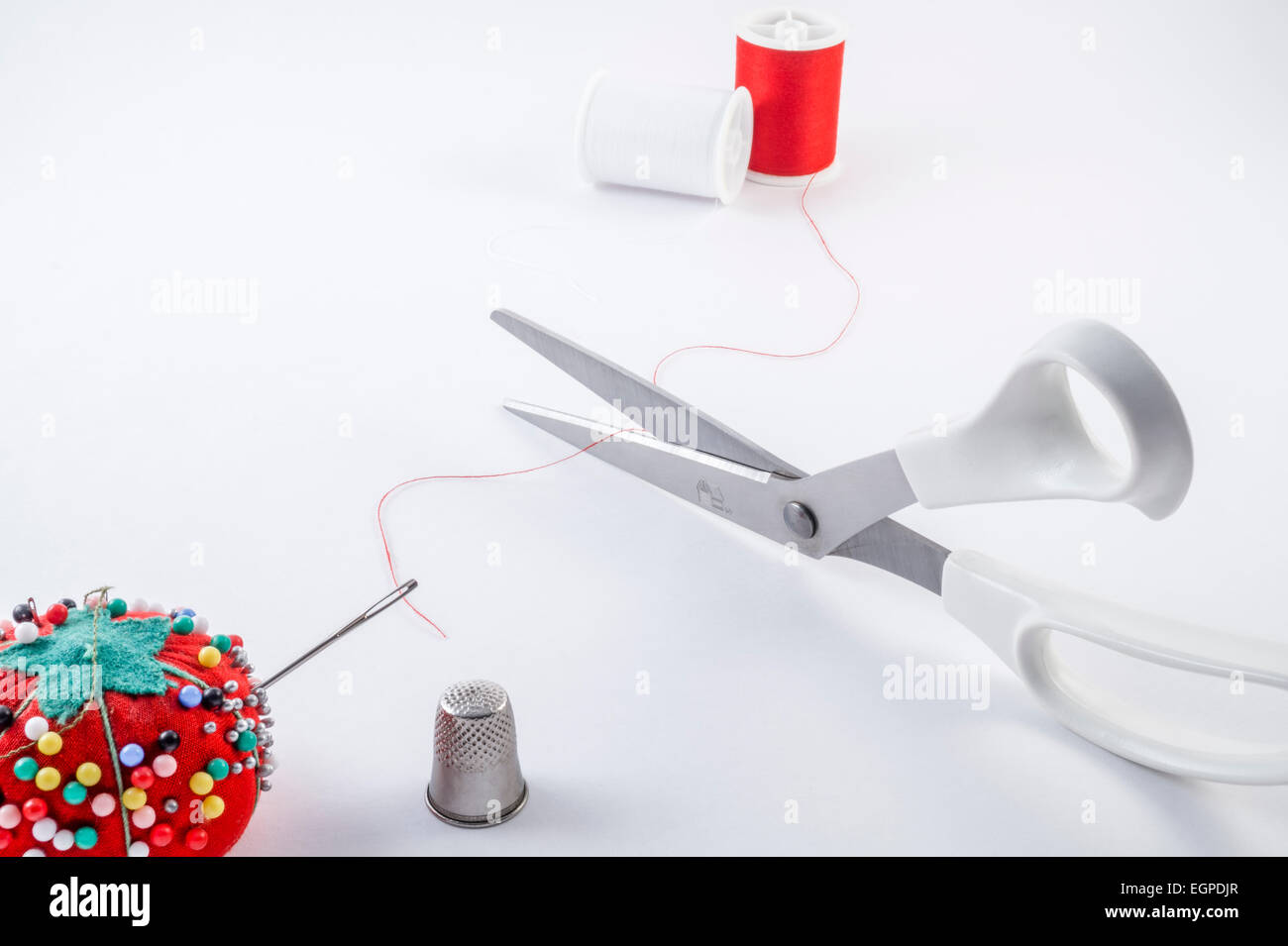 Spools of thread with sewing pins needle scissors and thimble on white ...