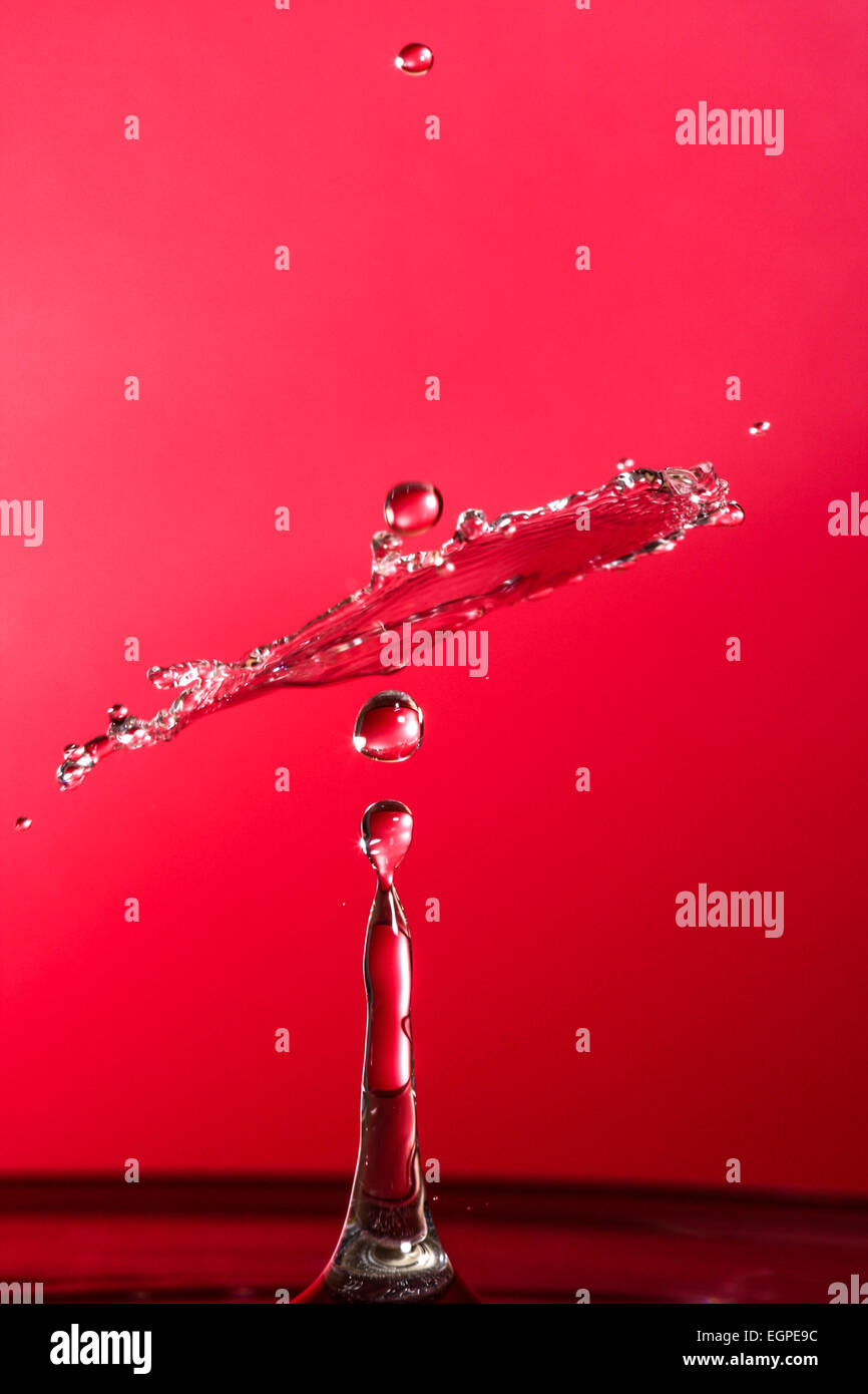 Water drop collisions with a red background Stock Photo - Alamy