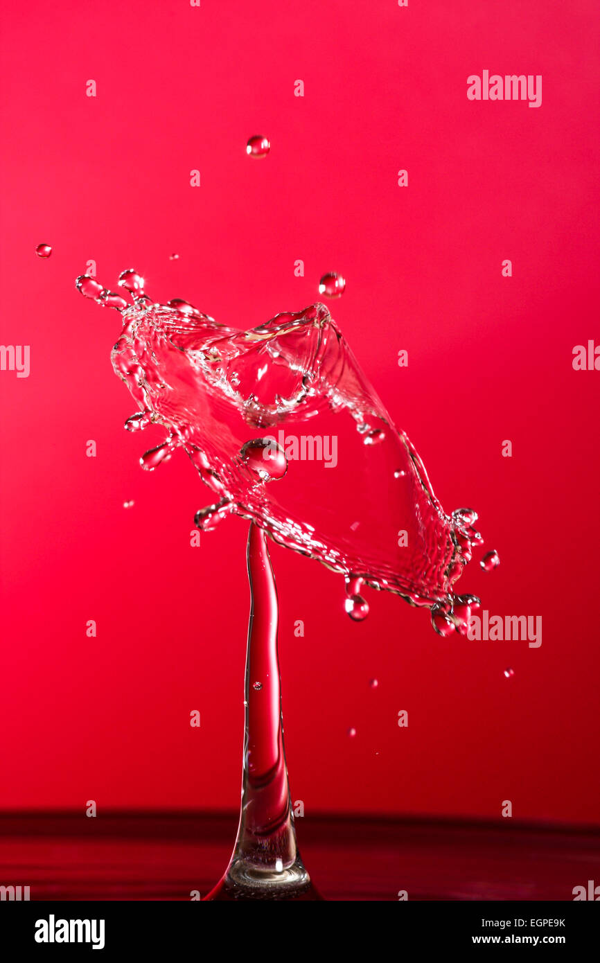 Water drop collisions with a red background Stock Photo - Alamy