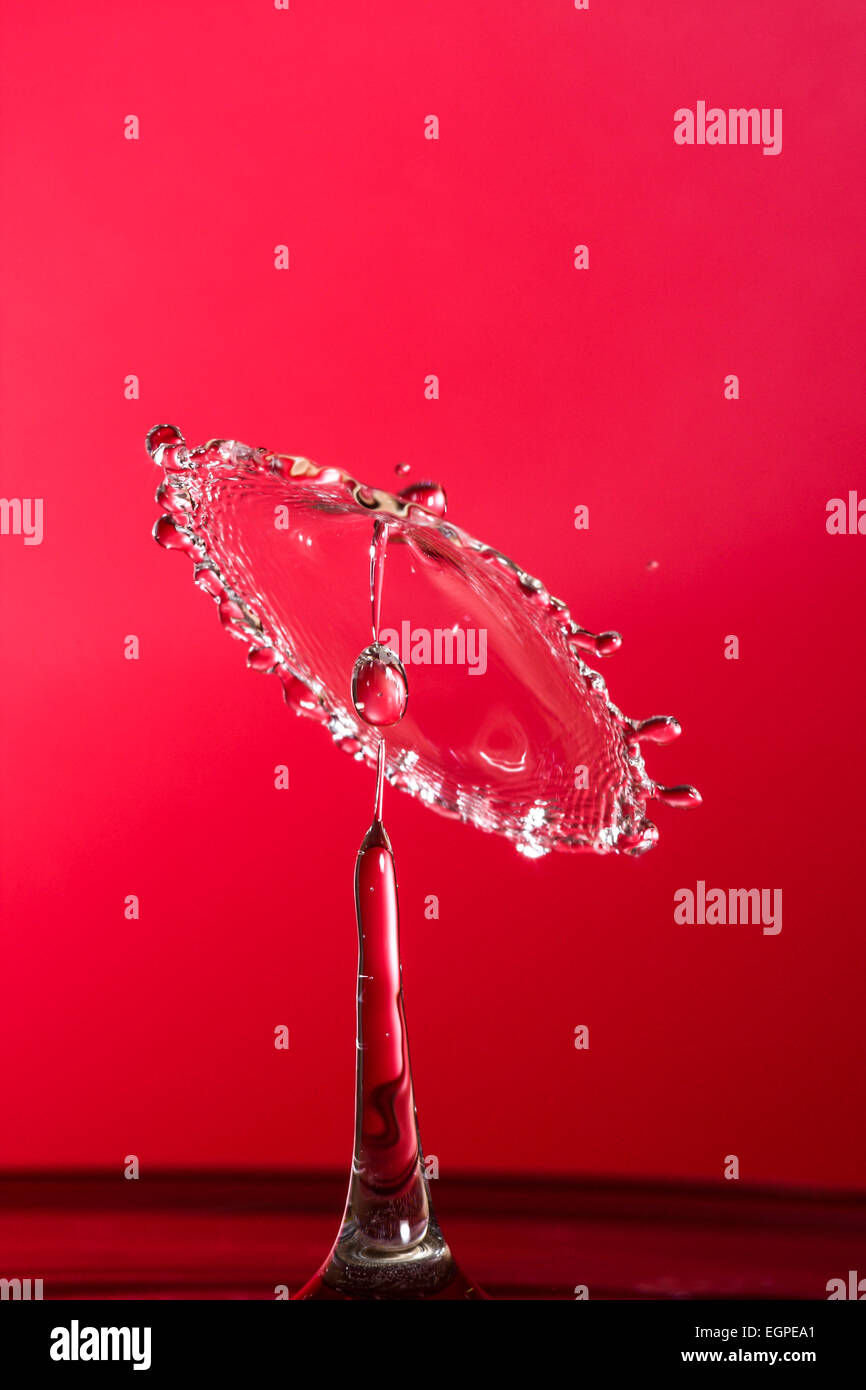 Water drop collisions with a red background Stock Photo - Alamy
