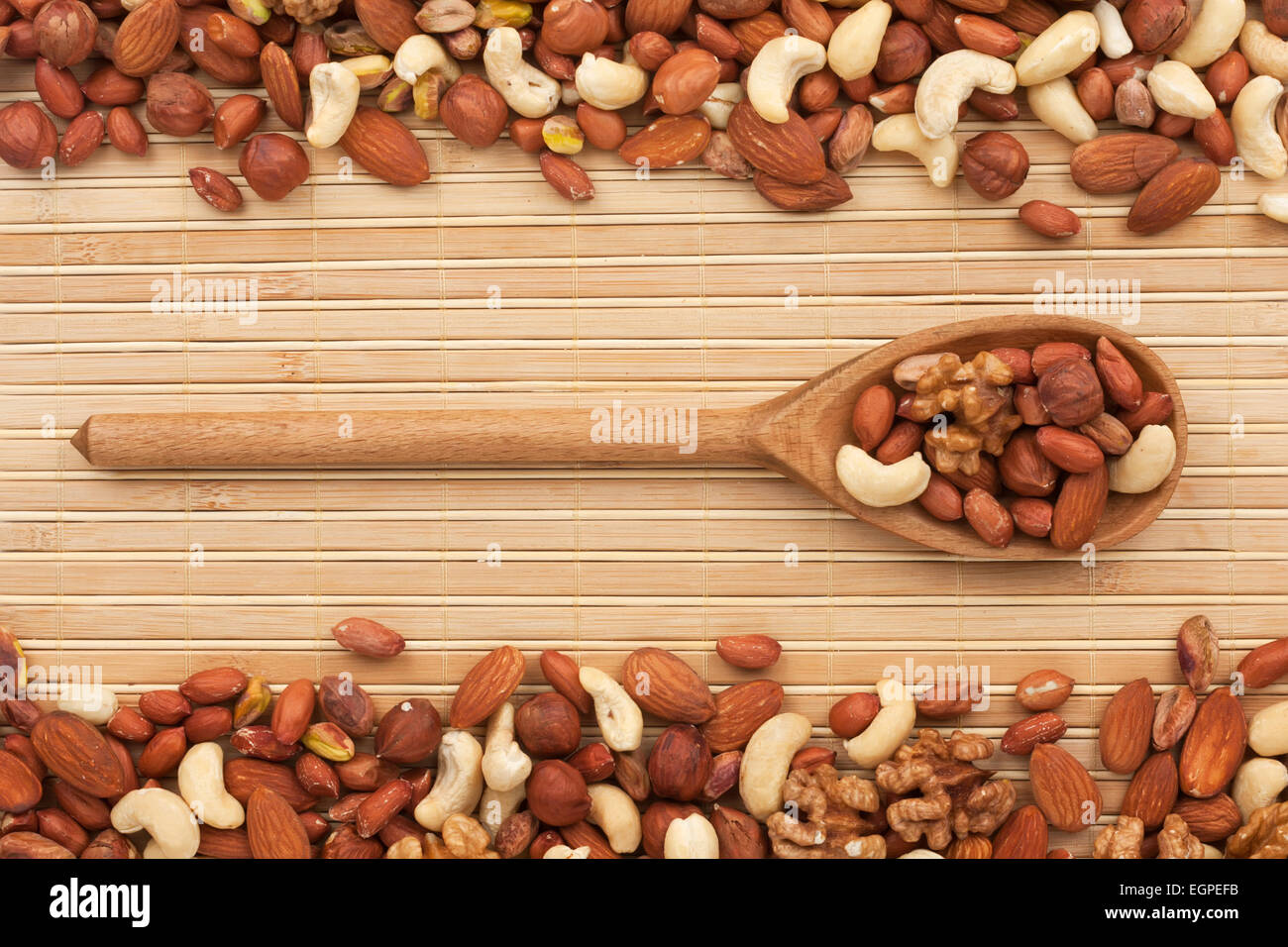Wooden spoon with dried nuts lying on bamboo mat Stock Photo - Alamy