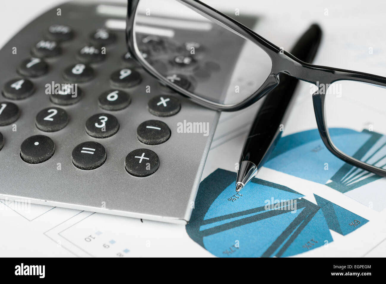Pen, calculator and glasses on a background of diagrams.Business ...