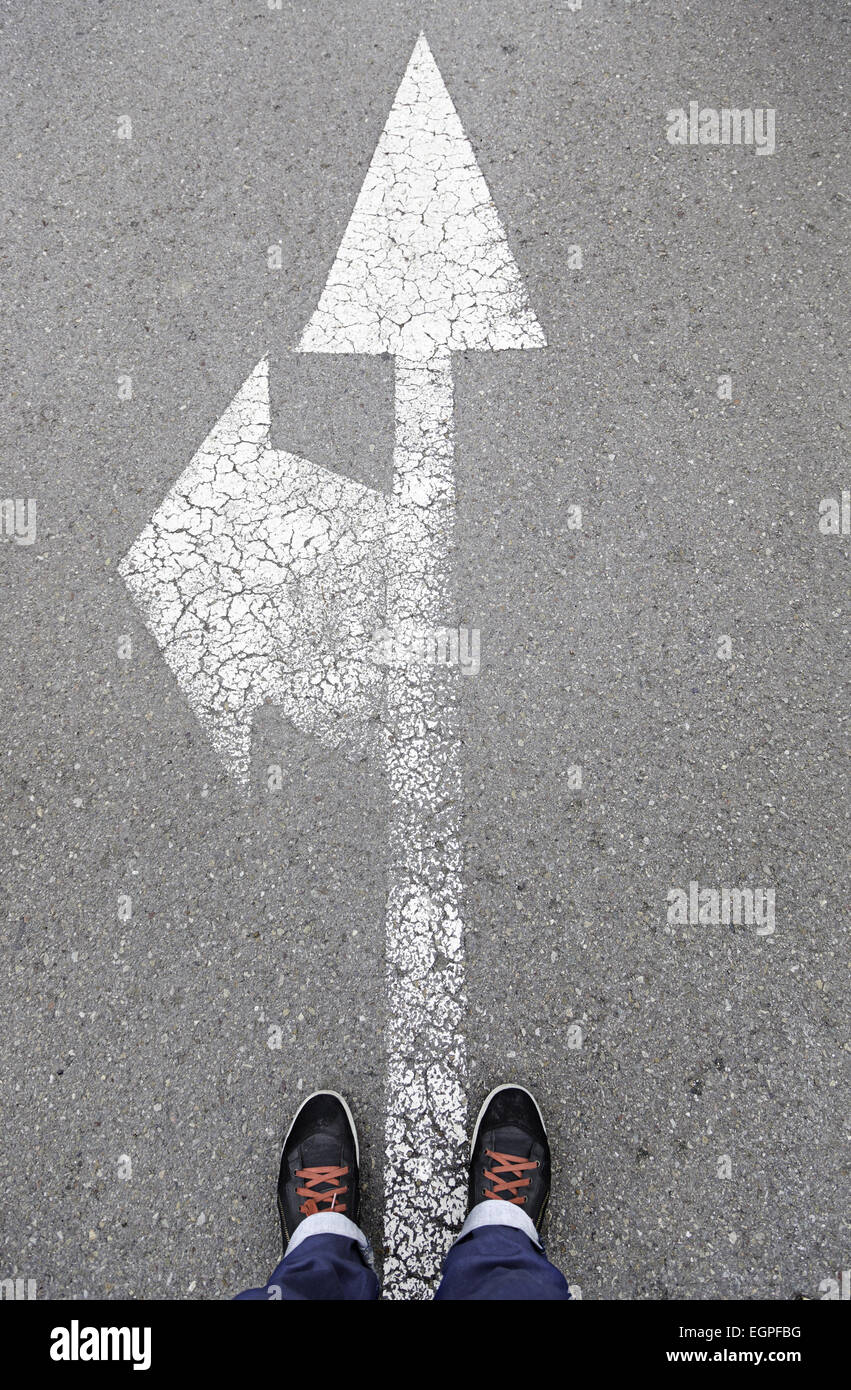 Directional arrow on the asphalt with a few feet, detail of a direction ...