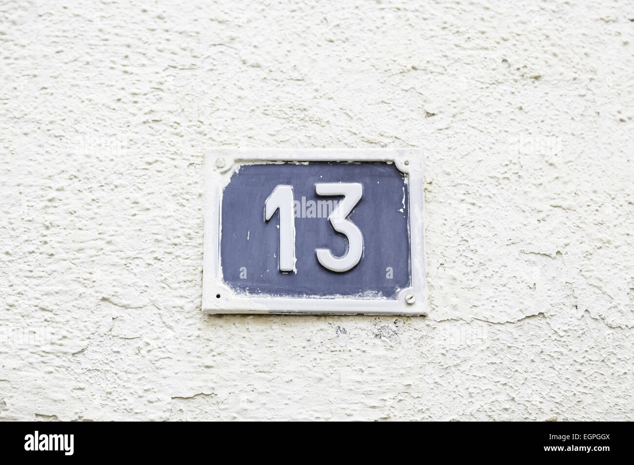 Number thirteen on a wall in a house, detail of a wall with a figure on ...