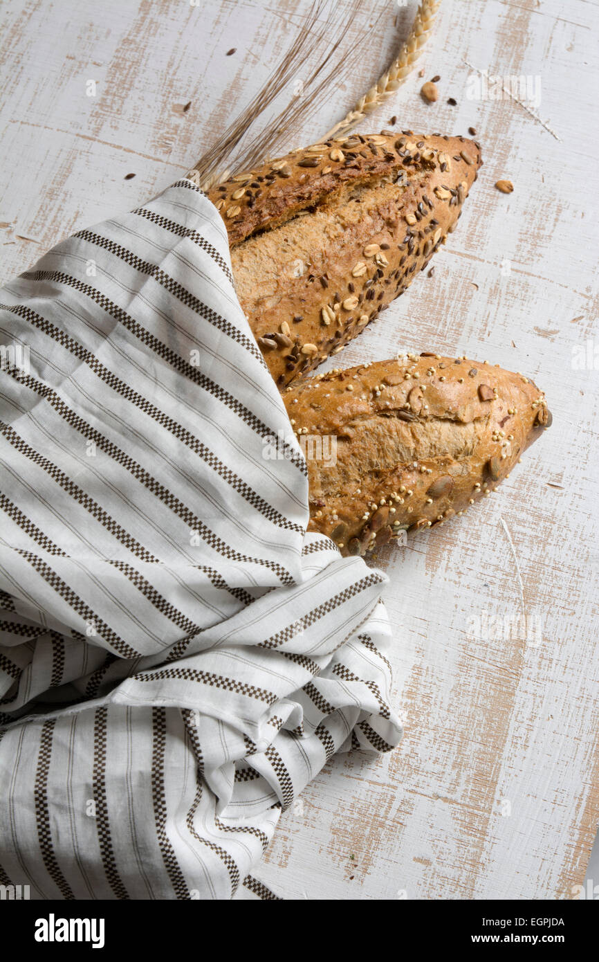 rustic seeded bread, wrapped in striped fabric on white wooden ...