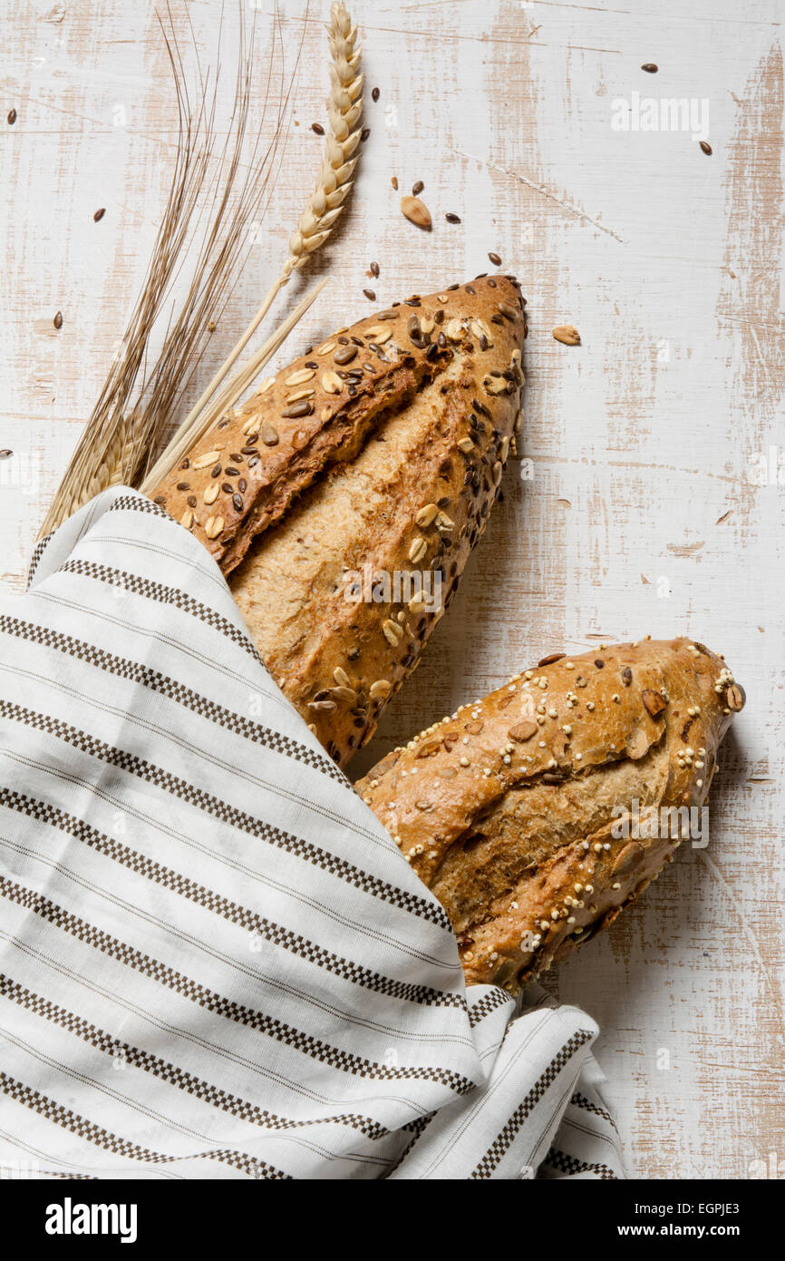 rustic seeded bread, wrapped in striped fabric on white wooden ...