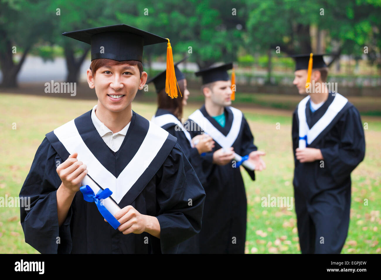 happy students in graduation gowns on university campus Stock Photo - Alamy