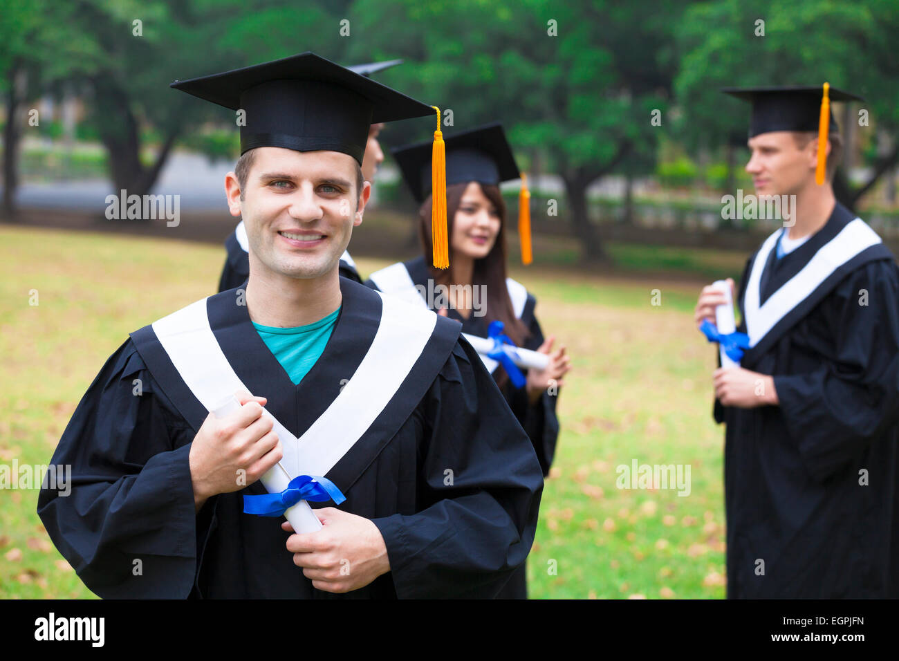 happy students in graduation gowns on university campus Stock Photo - Alamy