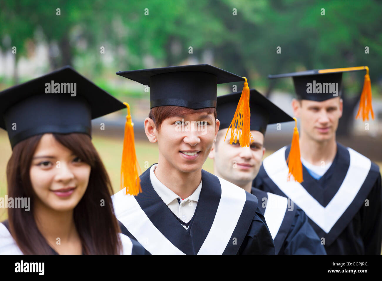 happy students in graduation gowns on university campus Stock Photo - Alamy