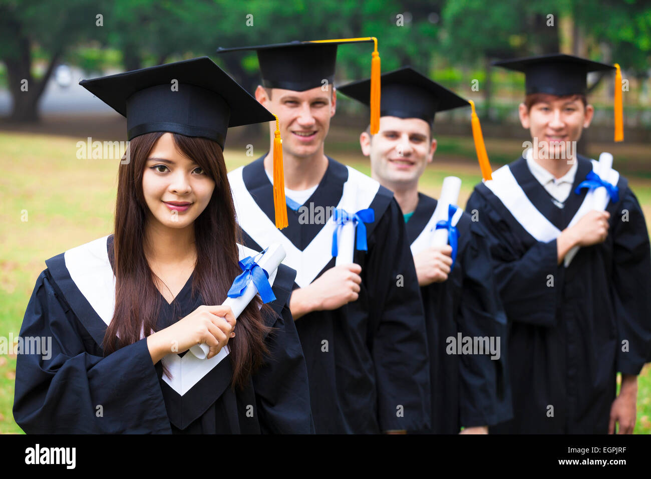 happy students in graduation gowns on university campus Stock Photo - Alamy