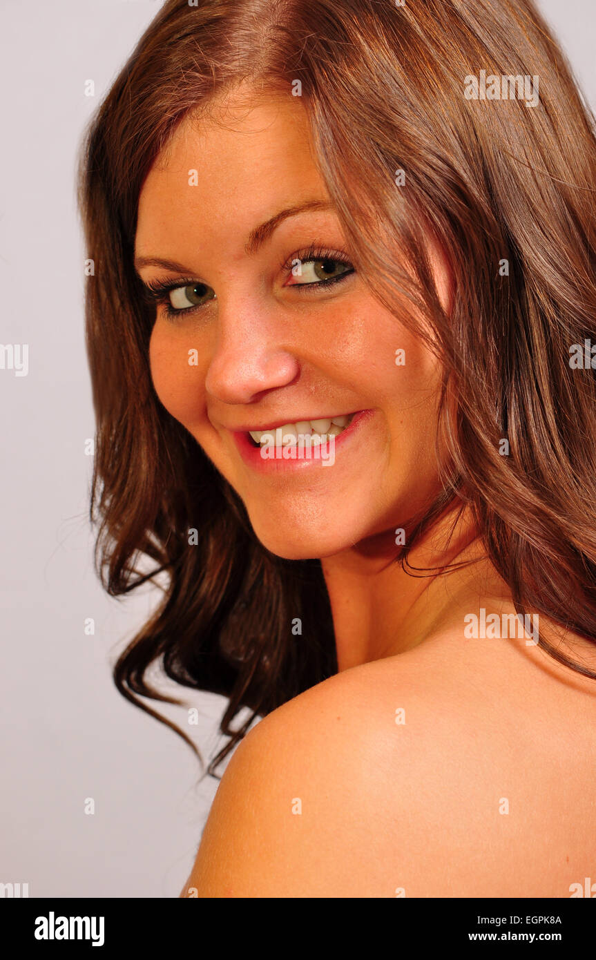 A pretty girl is looking over the shoulder smiling looking into the ...