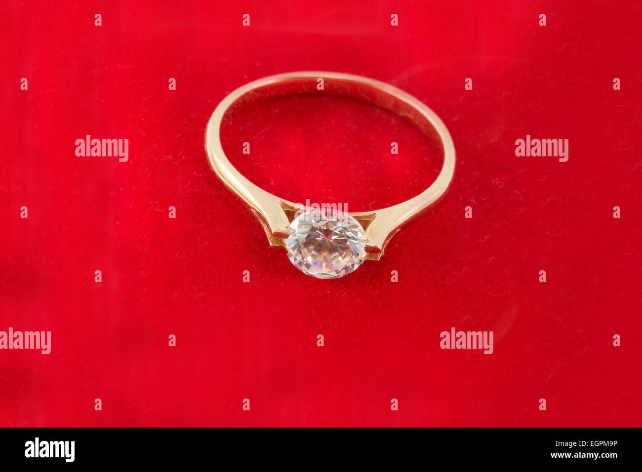 gold ring on red background Stock Photo - Alamy