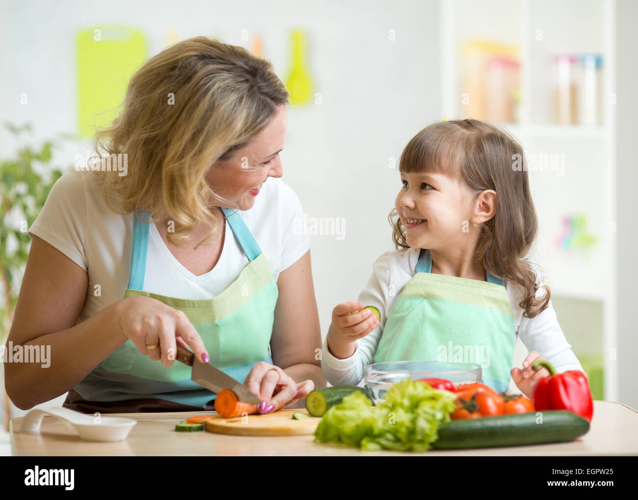 mother and daughter cooking and cutting vegetables on kitchen Stock ...