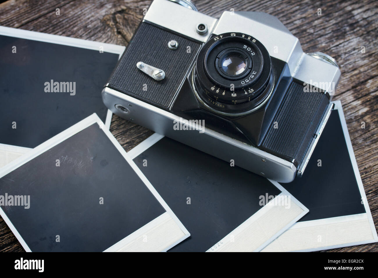 vintage photo camera on pile of old instant photos on wooden table ...