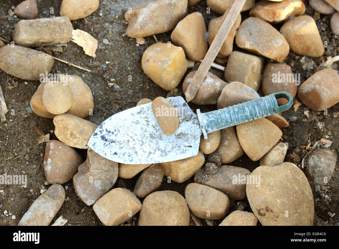 Pebbles and tools trowel, on the ground Stock Photo - Alamy