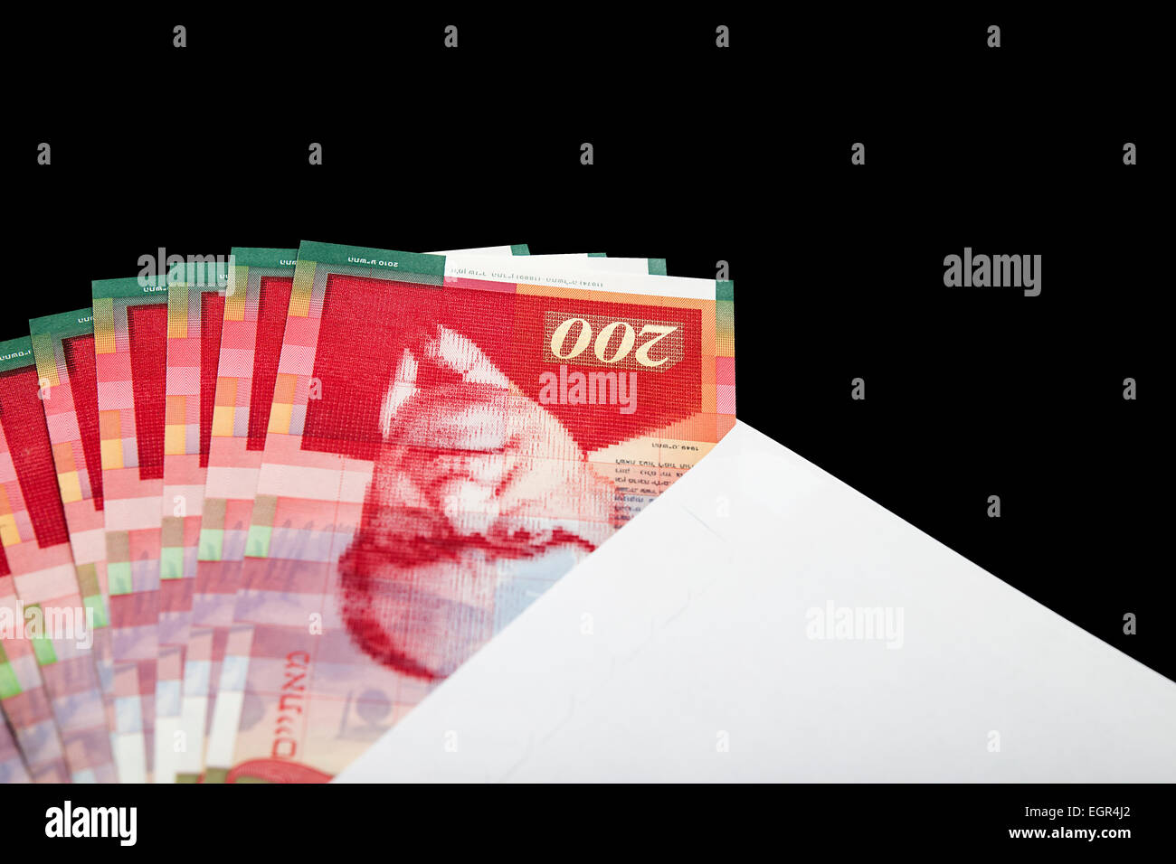 White envelope with bank notes, bills of NIS200 on a black background ...