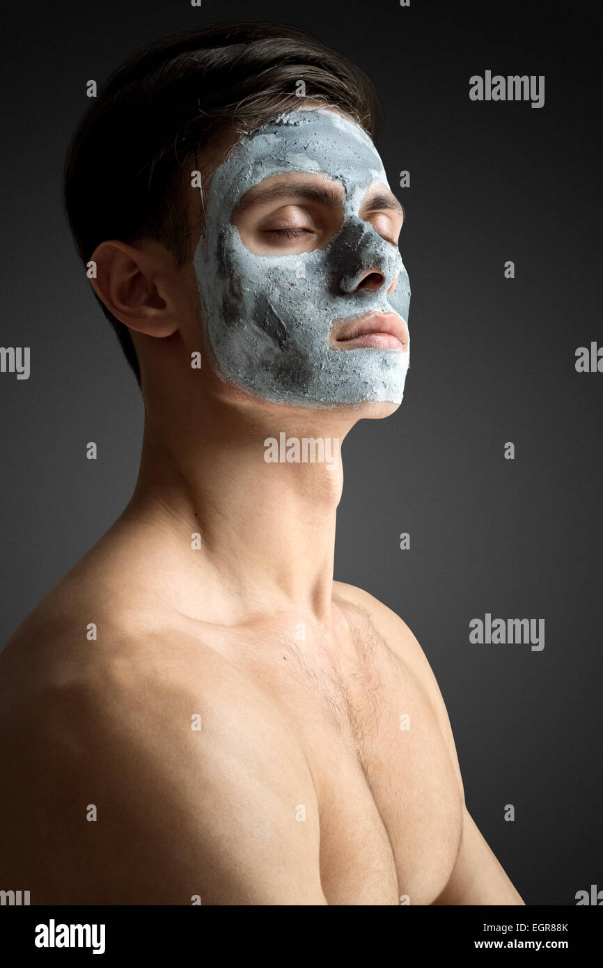 Portrait of a beautiful young man with a facial clay mask, face and ...