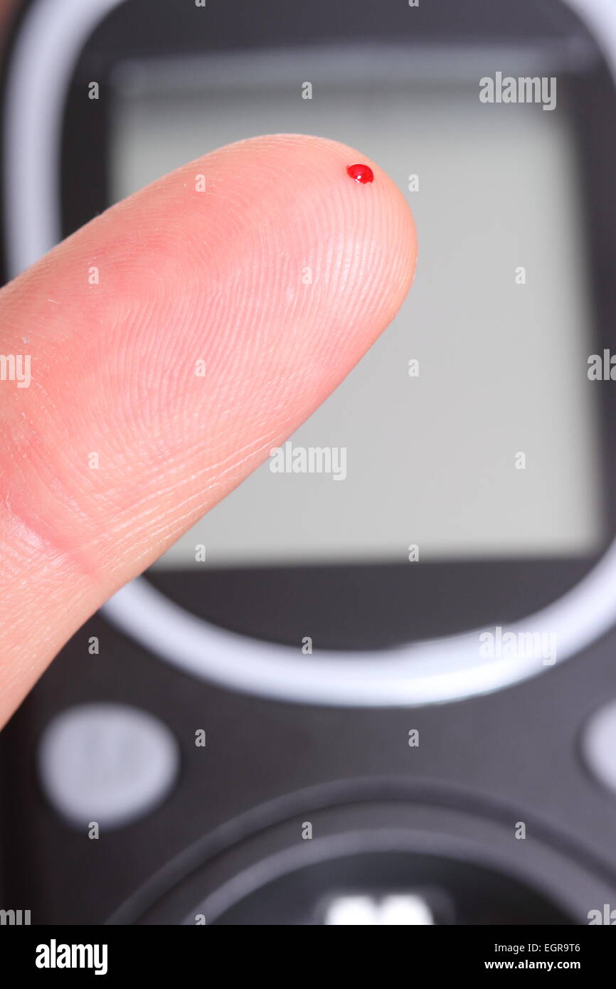 Closeup of finger with blood and glucose meter, taking blood sample ...