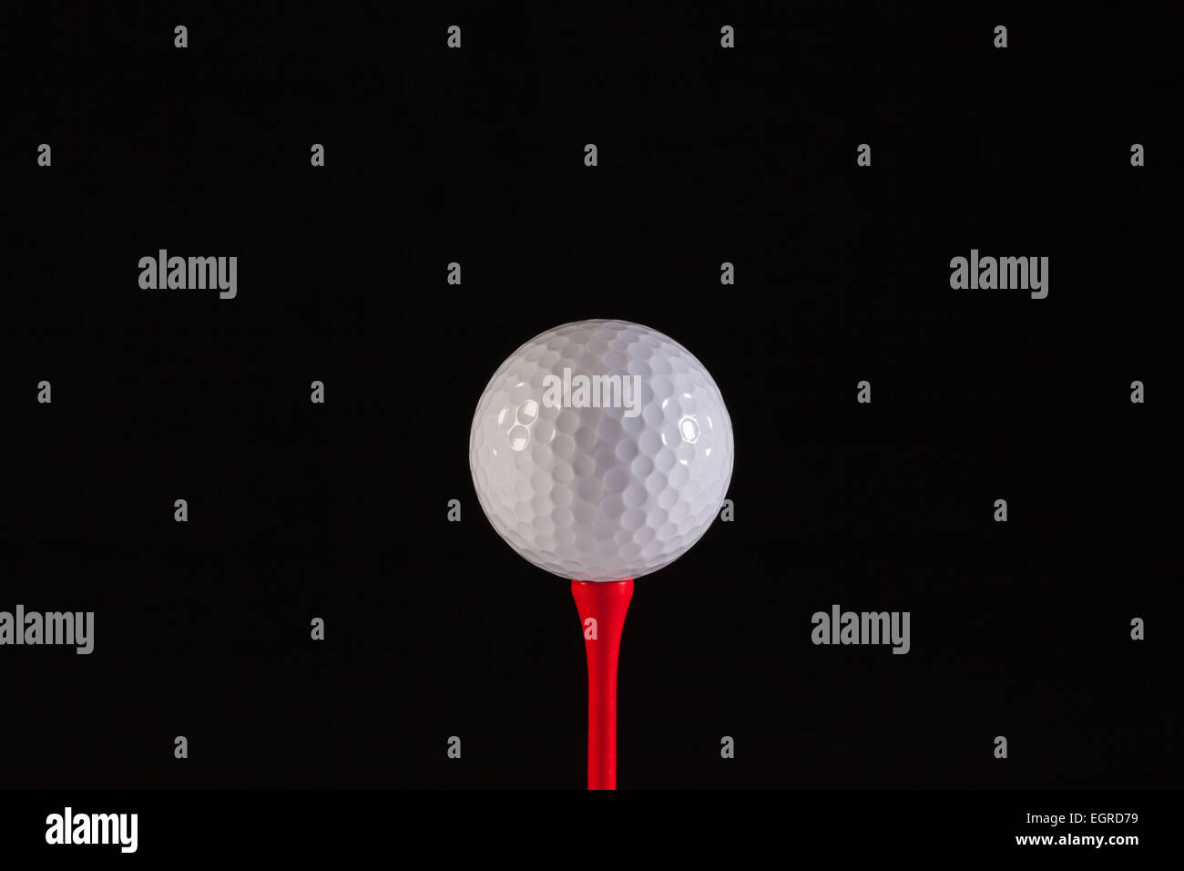 Golf ball and red tee on a black background Stock Photo - Alamy
