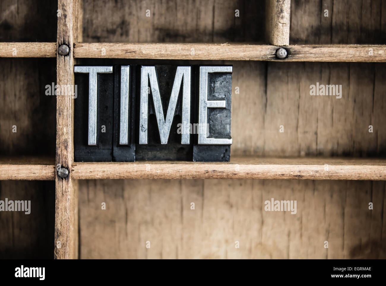The word "TIME" written in vintage metal letterpress type in a wooden ...