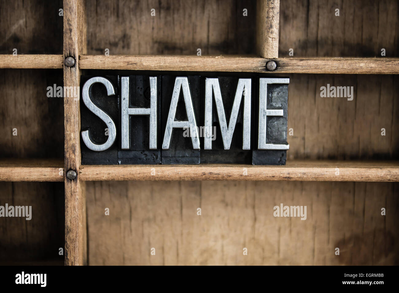 The word "SHAME" written in vintage metal letterpress type in a wooden ...