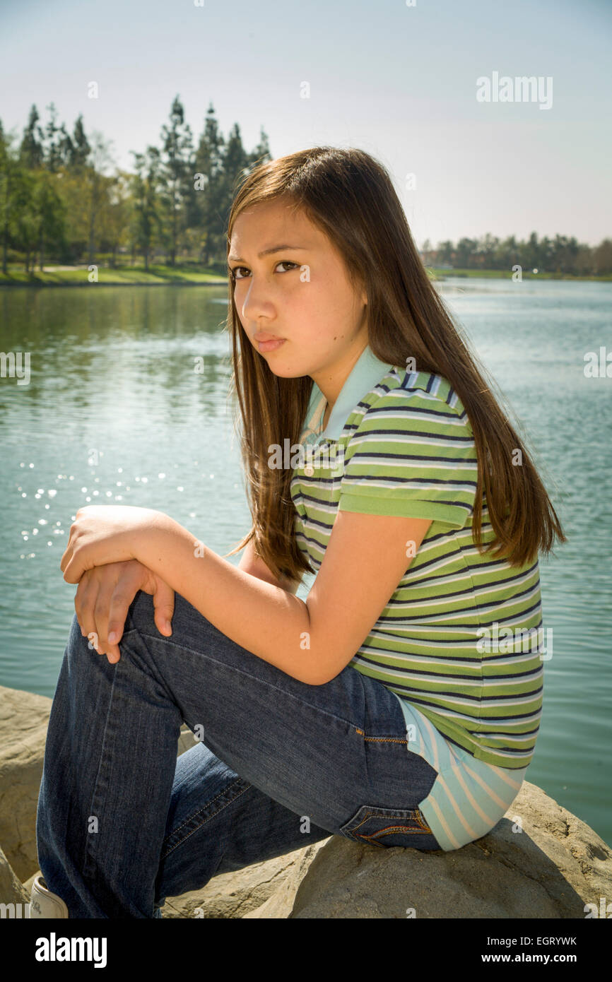 Vietnamese/Caucasian girl sits meditating 11-13 year years old outside ...