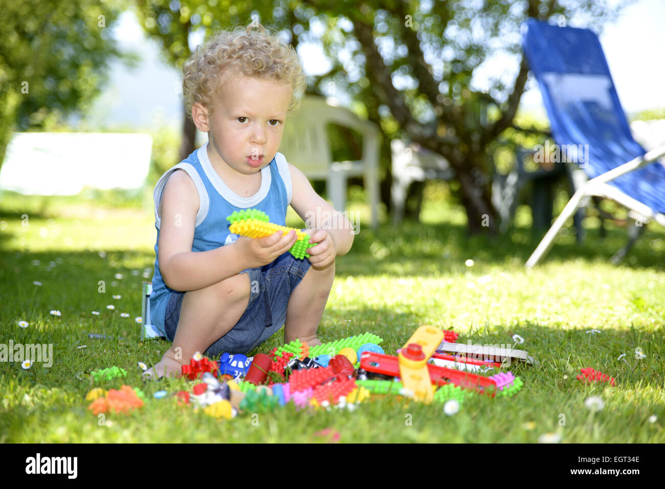 Baby playing on the lawn and winces Stock Photo - Alamy