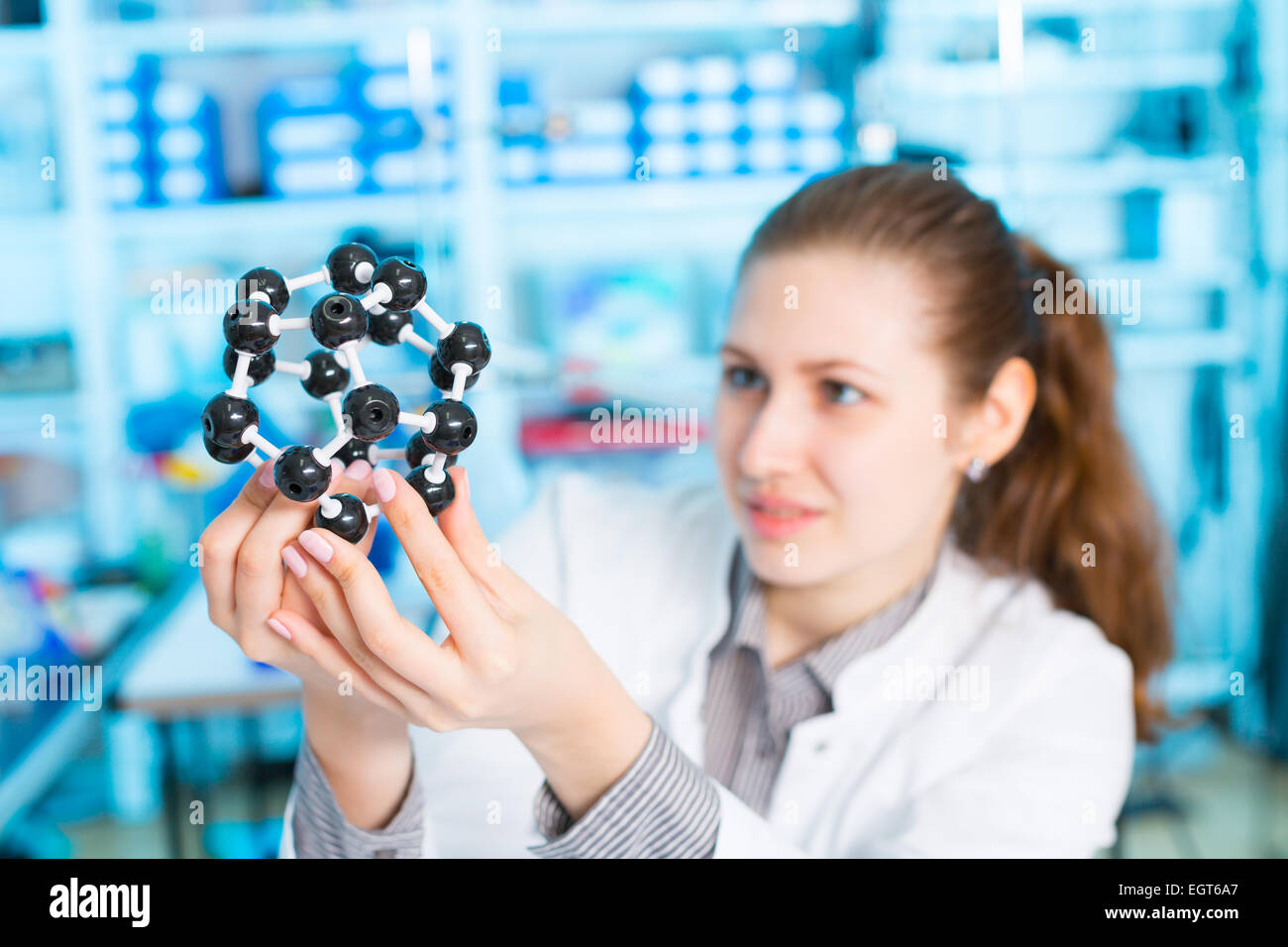 young woman scientist working at the laboratory. Model of molecule on a ...