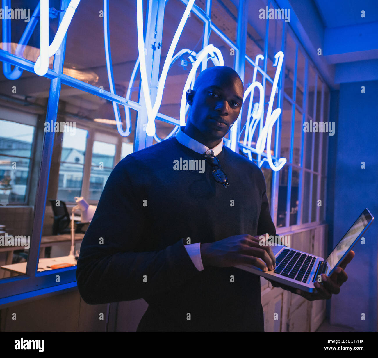 Young executive standing in office with a laptop. Business executive in ...