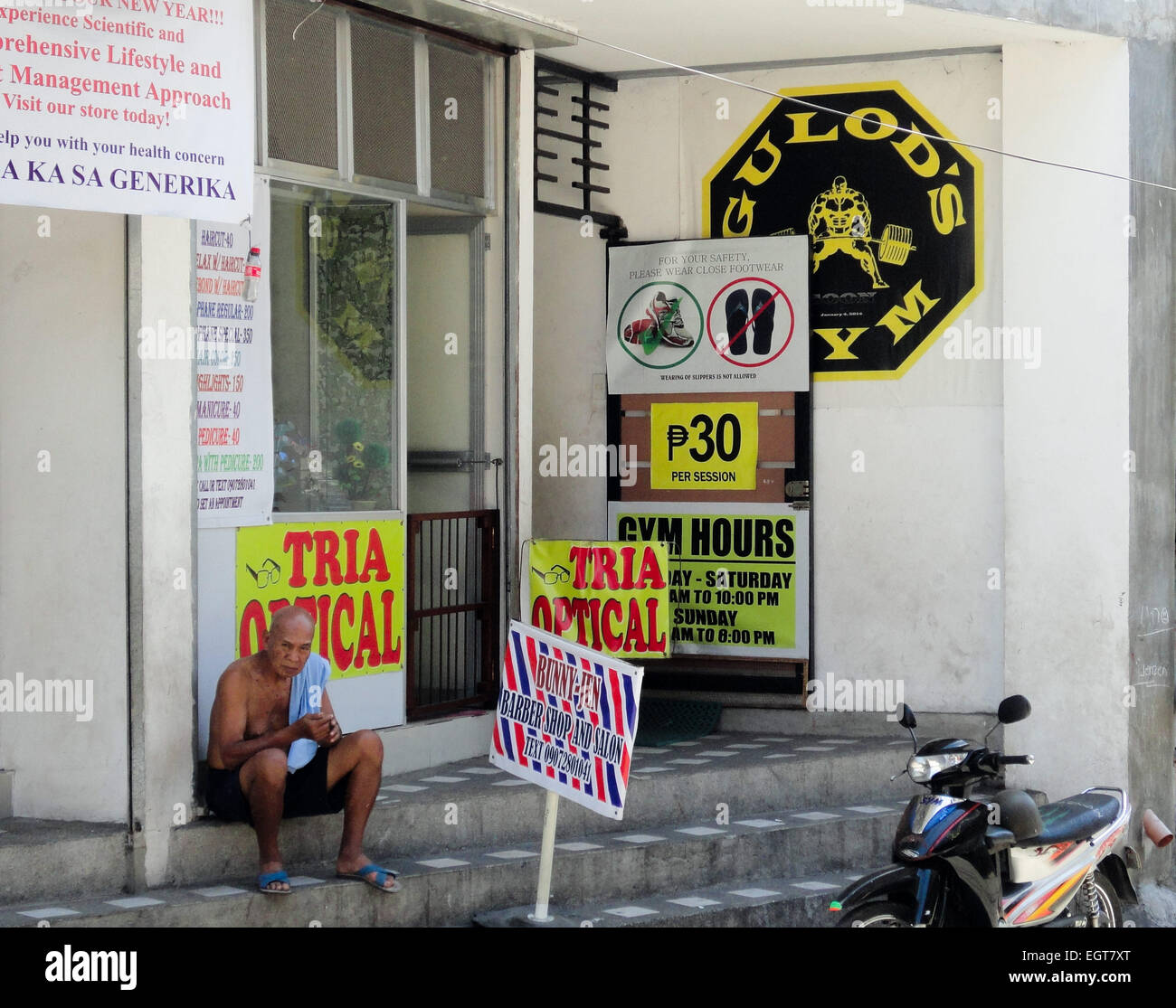 A Filipino man takes a rest outside a gym that lampoons the name of ...