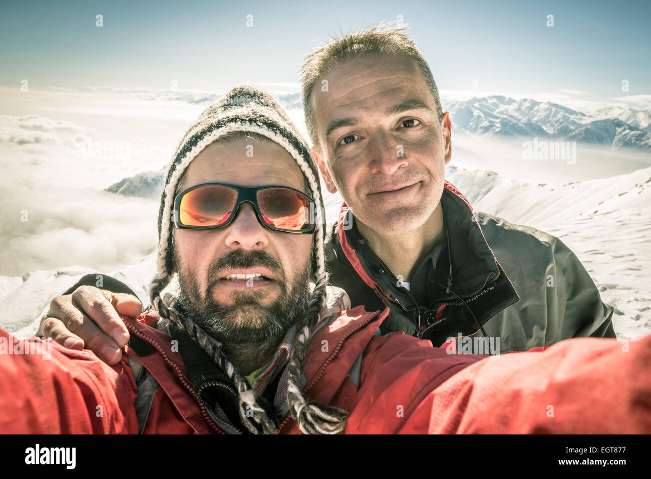 Adult european men taking selfie on the mountain summit with snowcapped ...