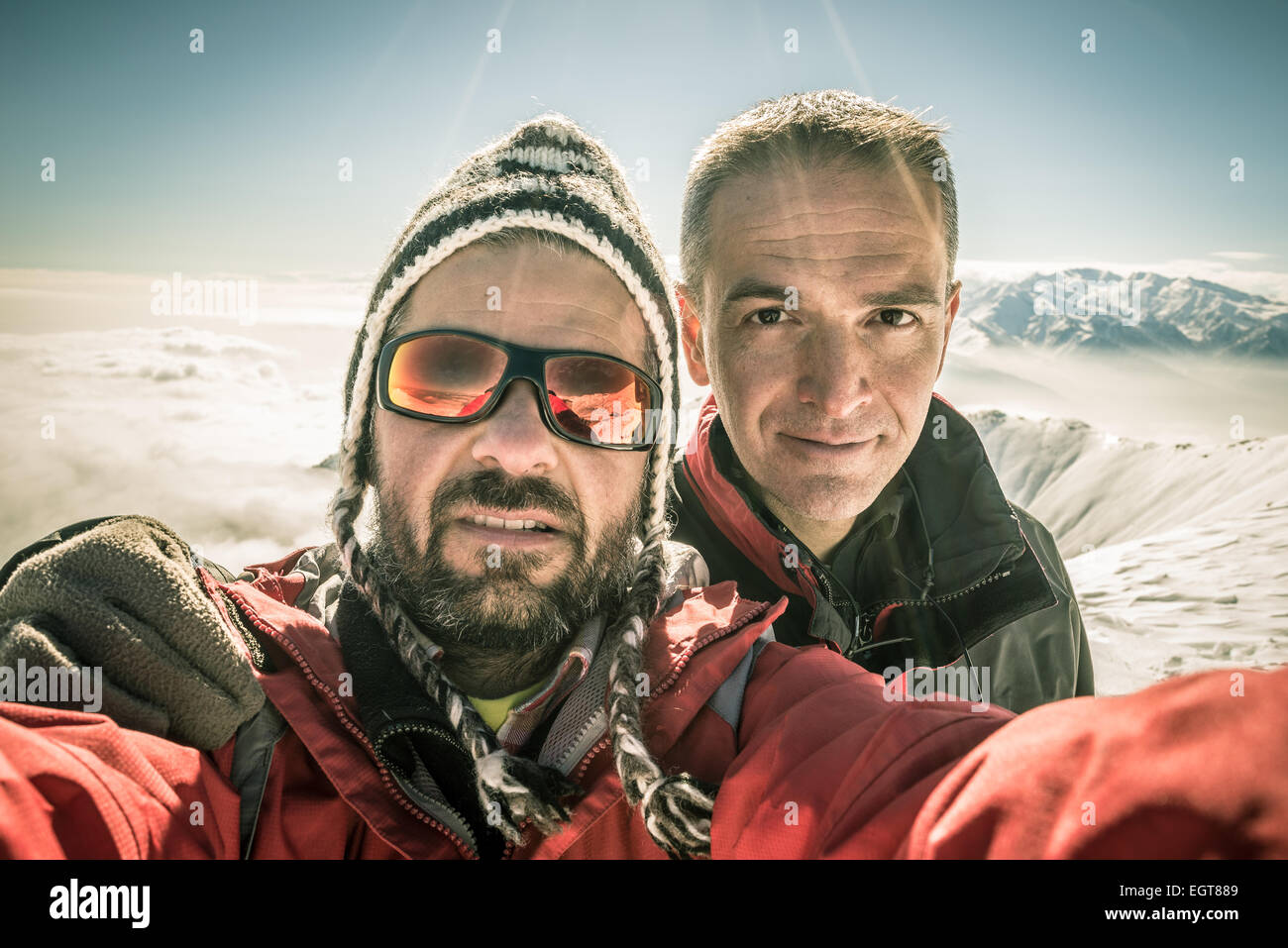 Adult european men taking selfie on the mountain summit with snowcapped ...