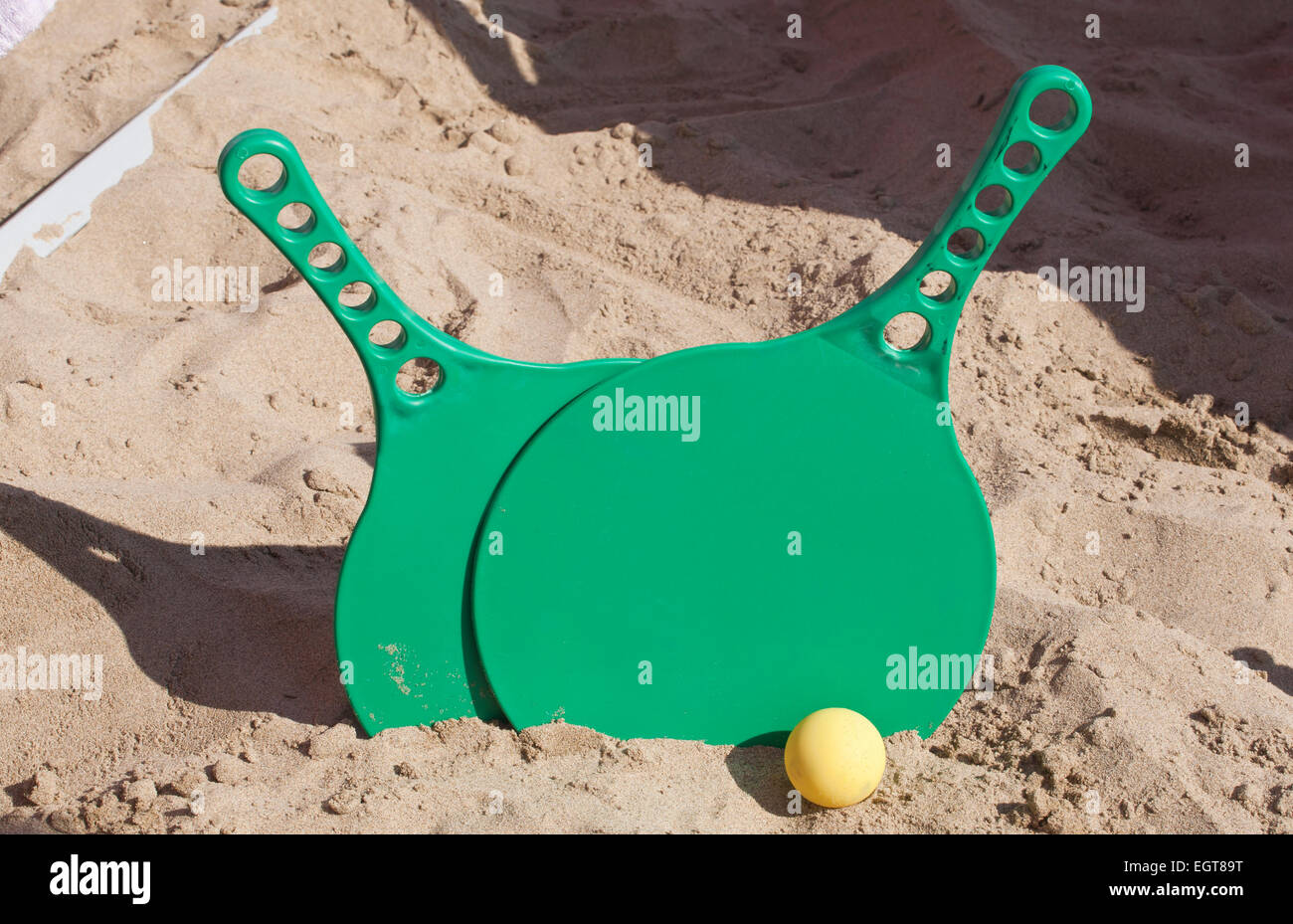Two green rackets and a ball on the sandy beach Stock Photo - Alamy