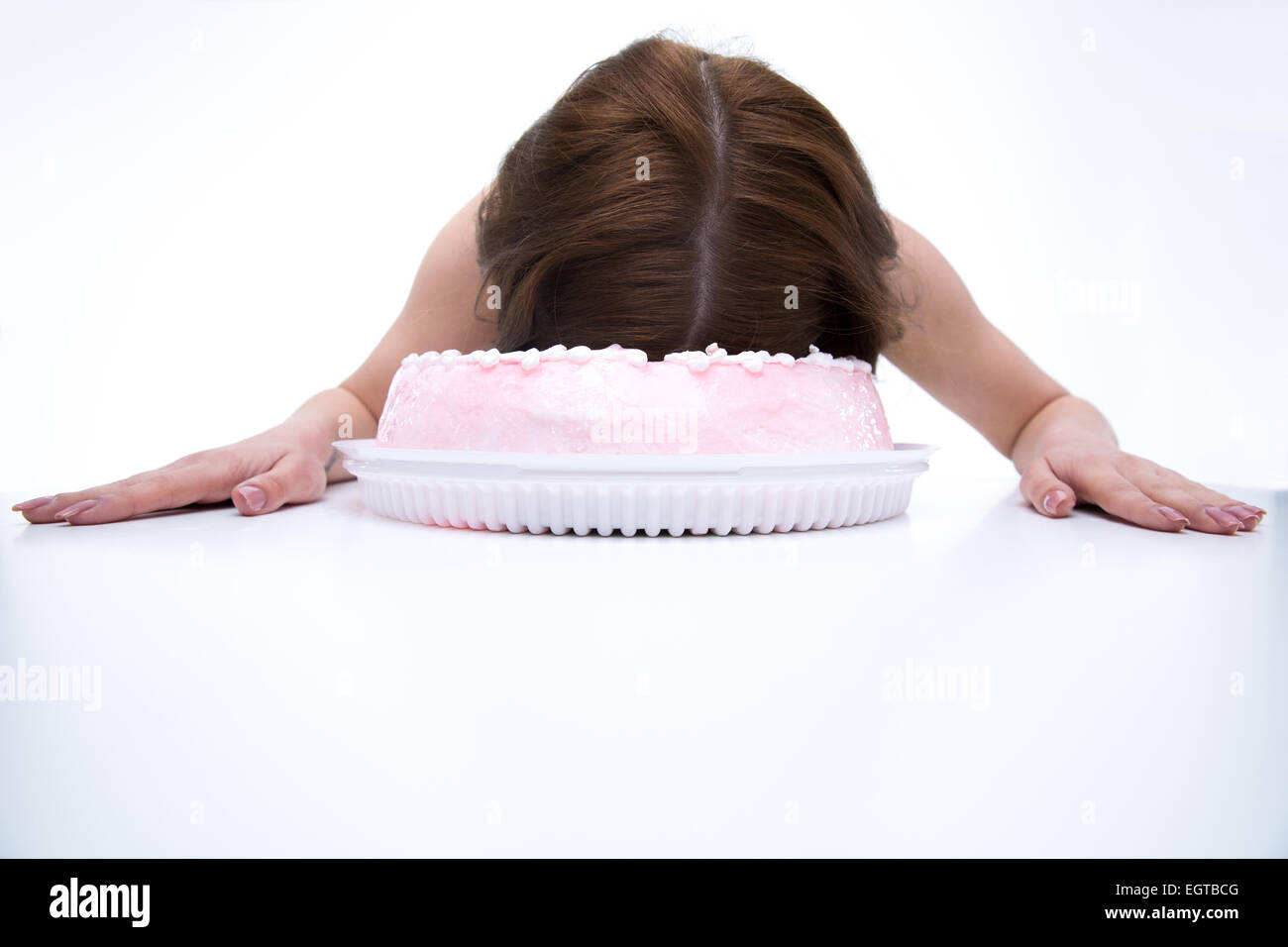 Woman lying on the table with face in cake Stock Photo - Alamy