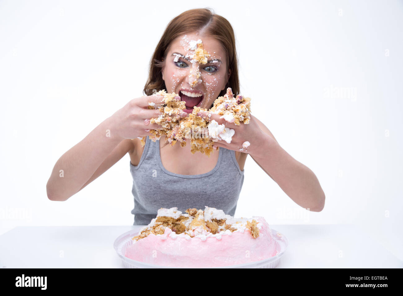 Angry young woman sitting at the table with cake at her face Stock ...