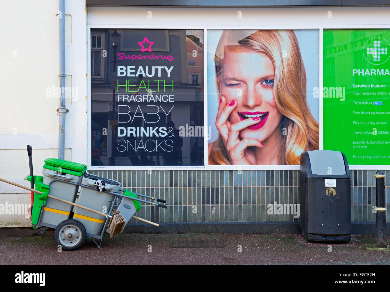 Poster of woman winking, with street-sweeper's cart and rubbish bin ...