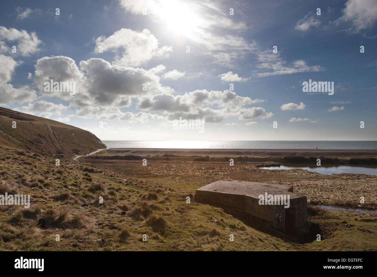 WWII concrete pillbox with a lagoon and shingle bar beyond and sea in ...