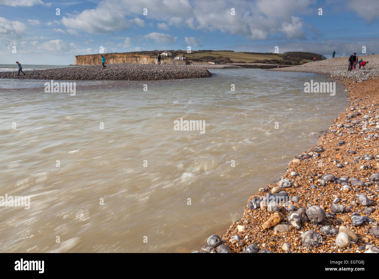 The estuary of the River Cuckmere flowing into the sea at high tide ...